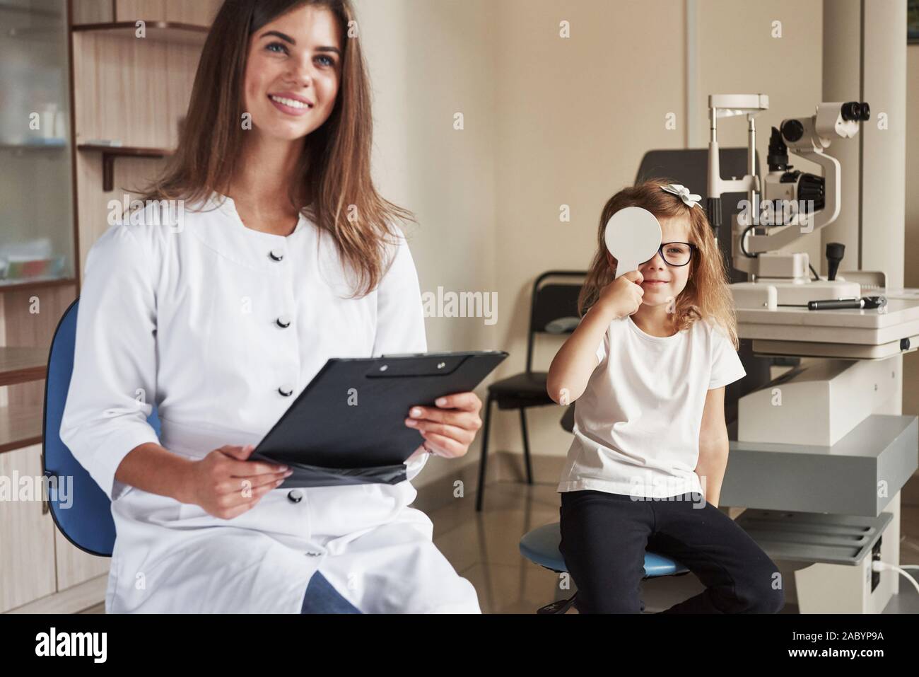 Front view. Doctor and little patient sits and conduct the test of the ...