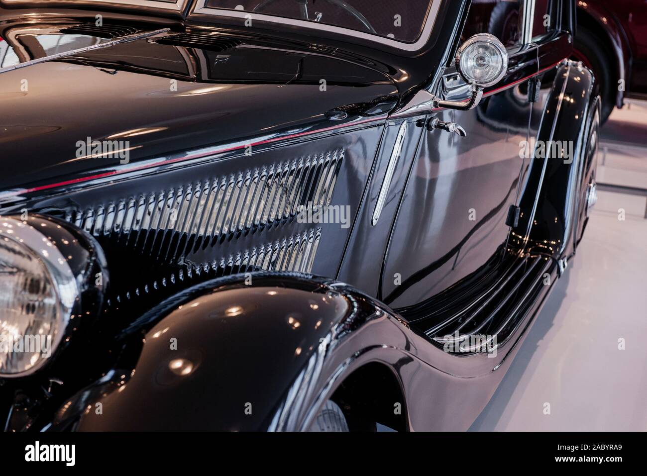Detailed photo of an old black shiny car standing or the white tile ...