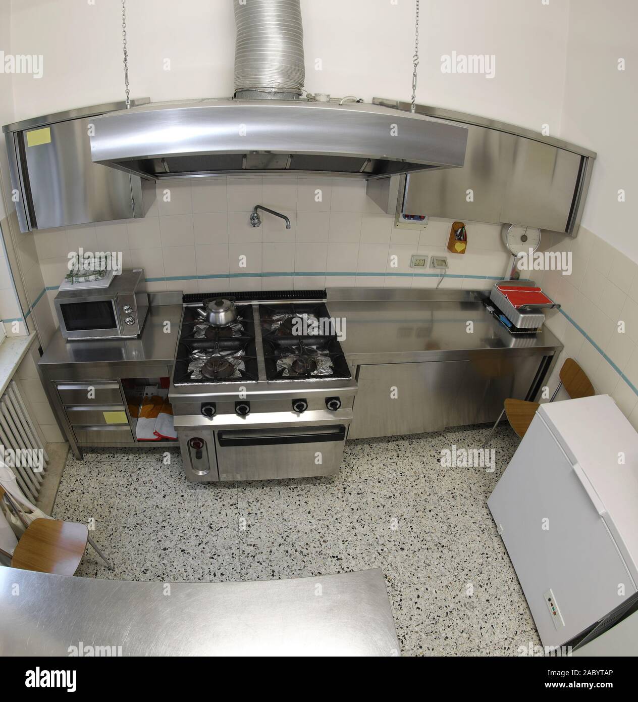 industrial kitchen with the huge extractor hood and the stove ...