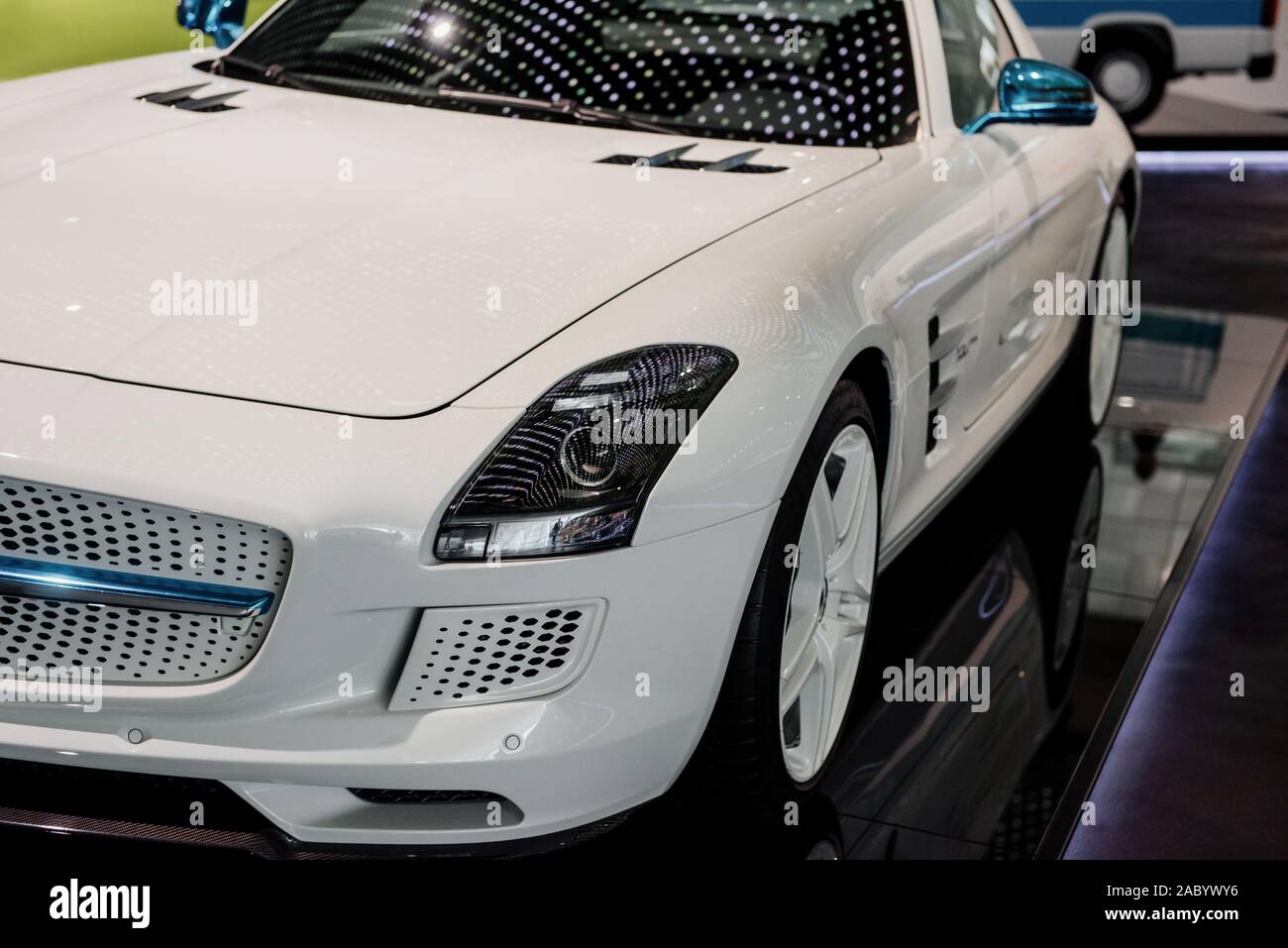 Front, side view of left headlight and radiator grille, blue mirror with turn signal, white ...