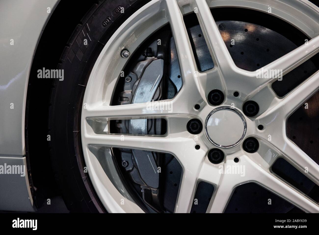 Close up shot of white light alloy wheels with brake disc pad, low-profile tires of a modern ...