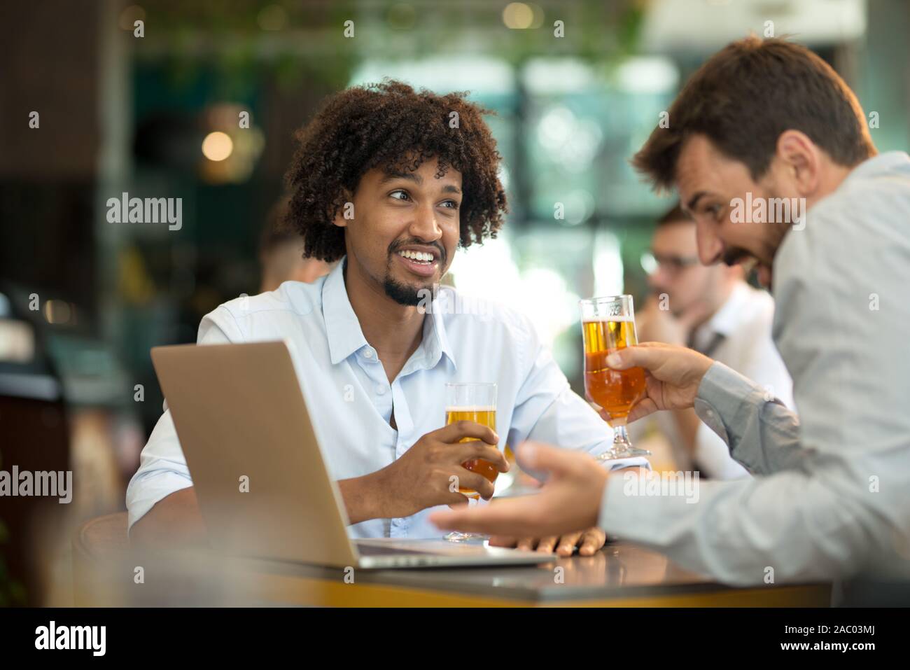 Young businessmen siting pub and drinking beer as they work Stock Photo ...