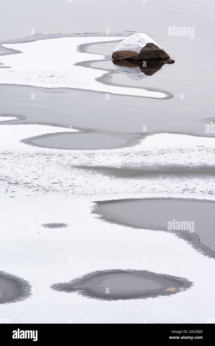 River begins to freeze, rock poking out of the shallow water Stock ...