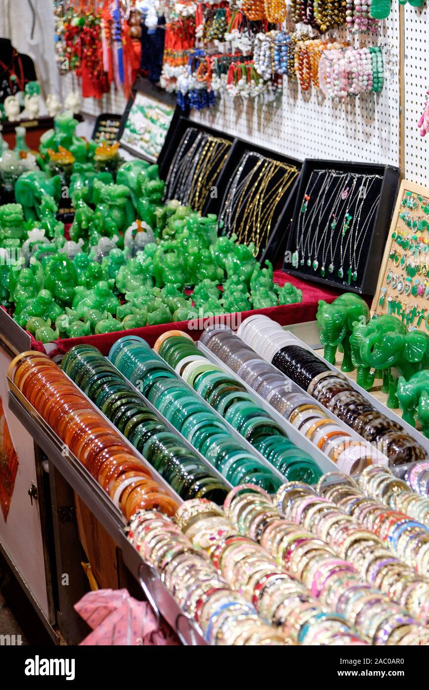 A vendor displays jade jewelry, including bangles, necklaces, and ...