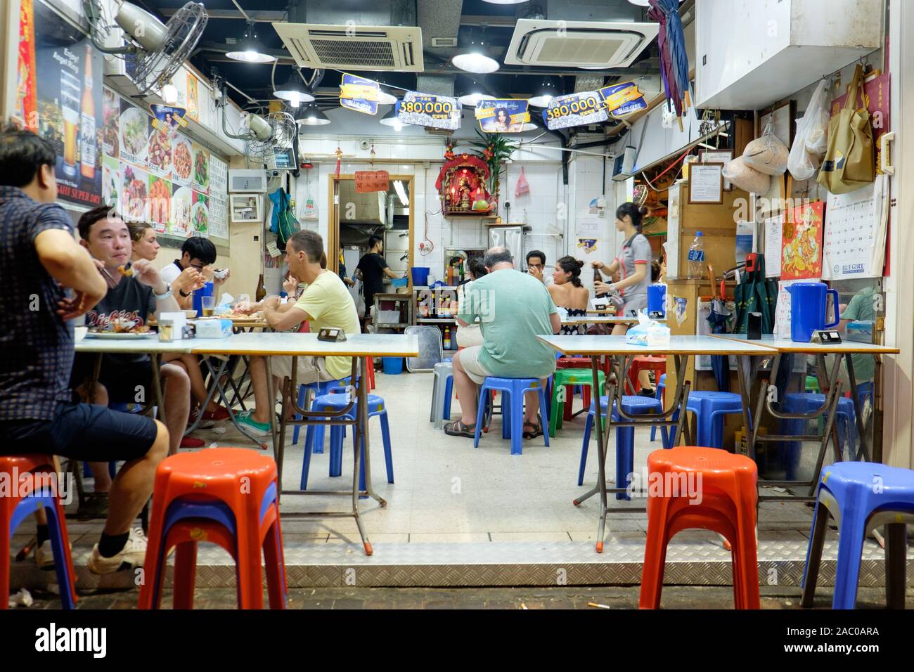 Diners enjoy a meal at a busy Hong Kong restaurant. The server brings ...