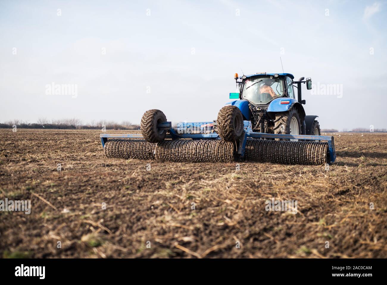 Tractor on the field cultivates the land Stock Photo - Alamy