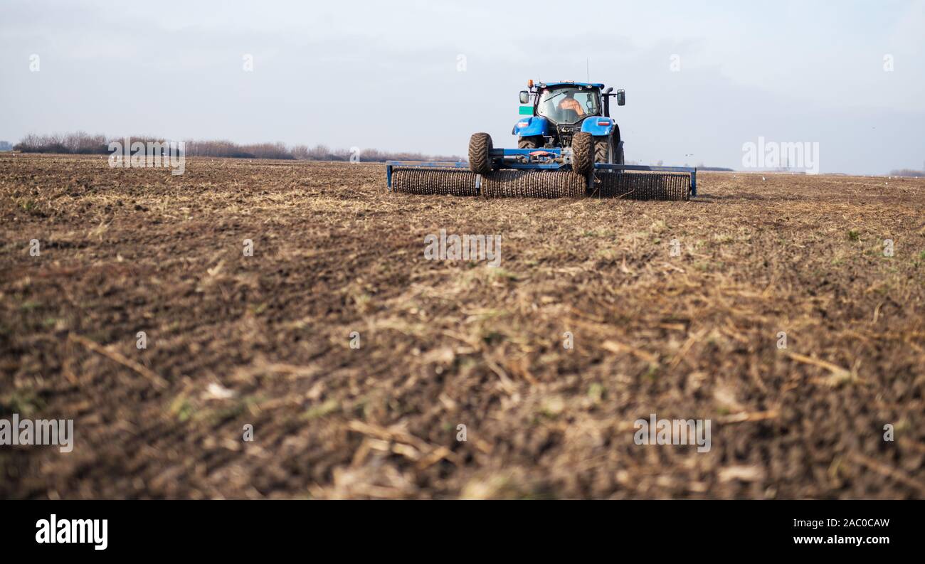 Tractor on the field cultivates the land Stock Photo - Alamy