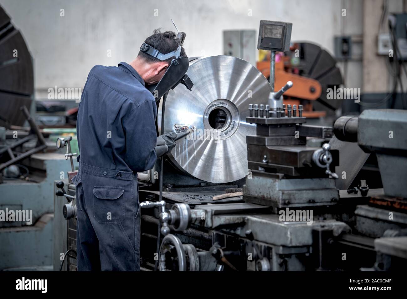 Workers is milling metal parts with lathes machines with high precision ...