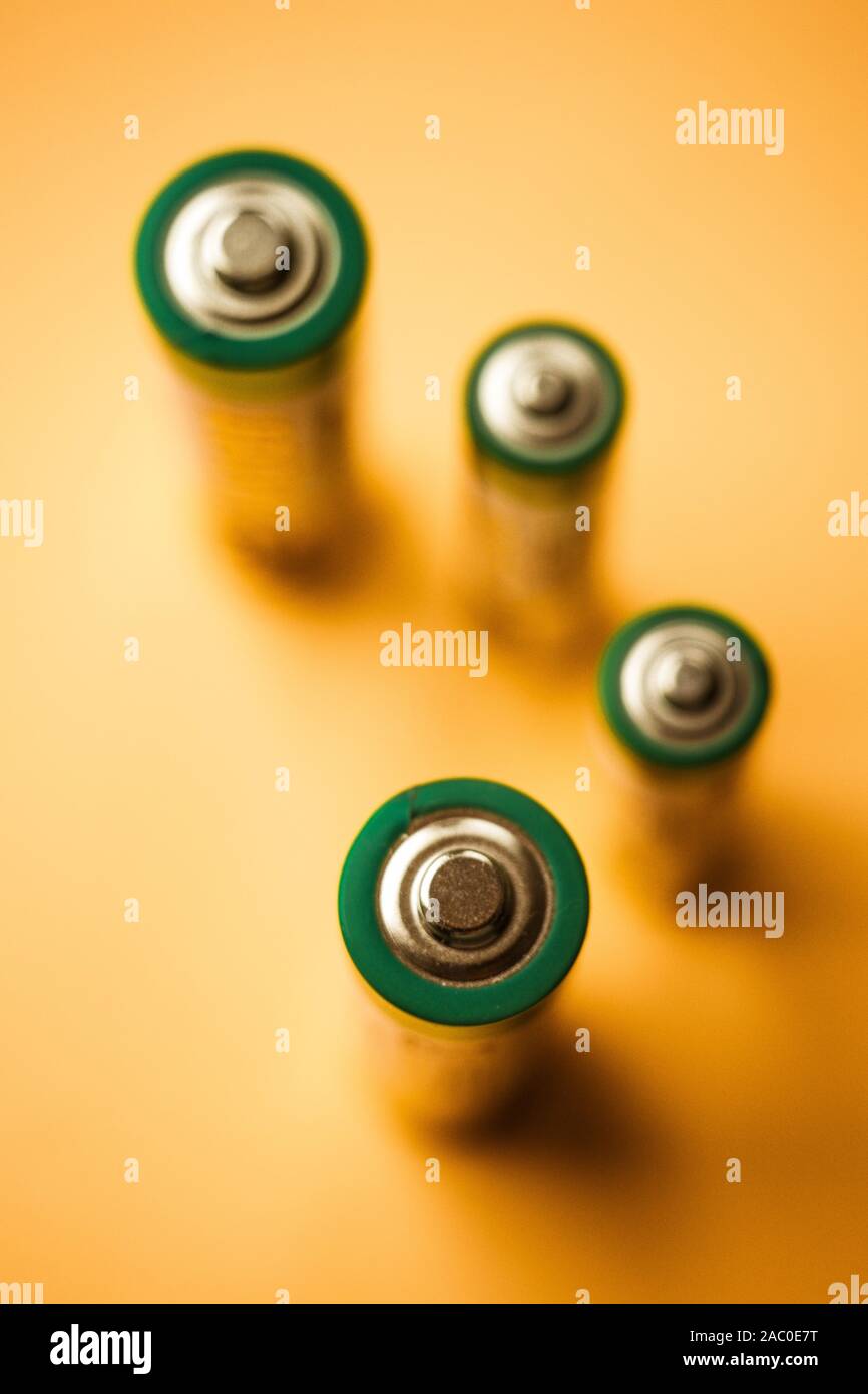 Four new batteries on the orange table, top view Stock Photo - Alamy