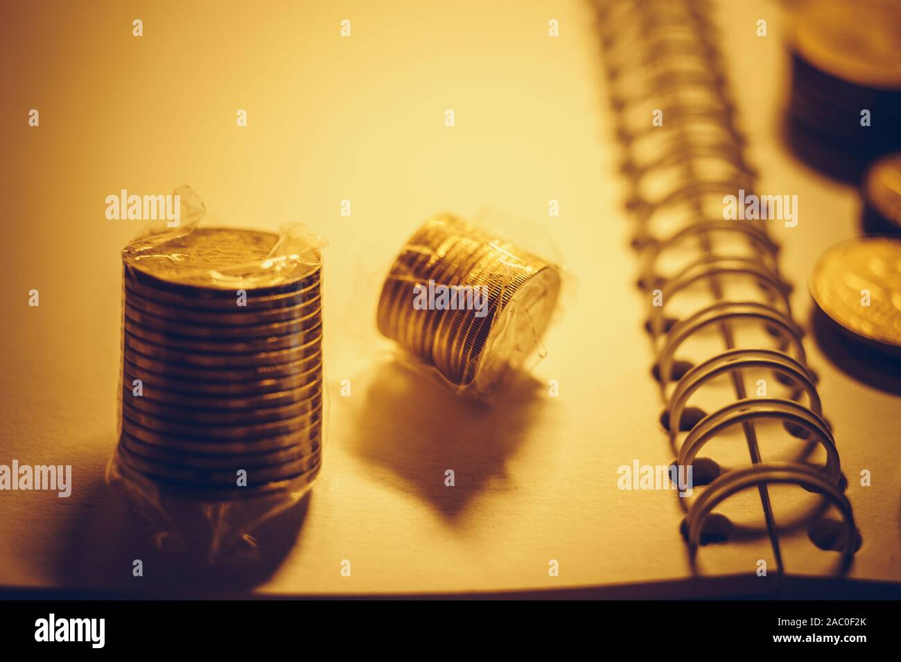 Collection of golden metal money on the notebook paper Stock Photo - Alamy