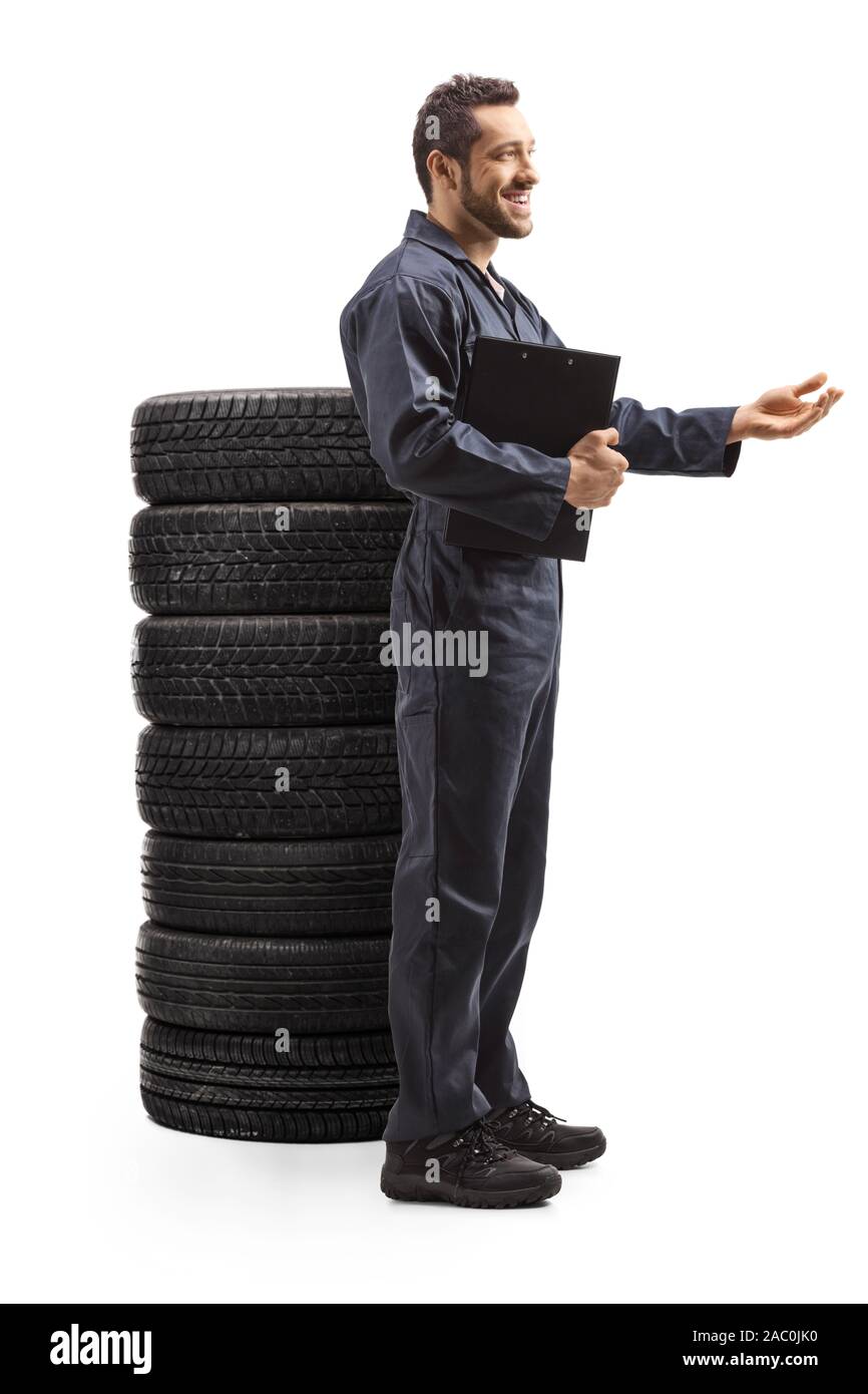 Full length profile shot of an auto mechanic standing with a pile of ...