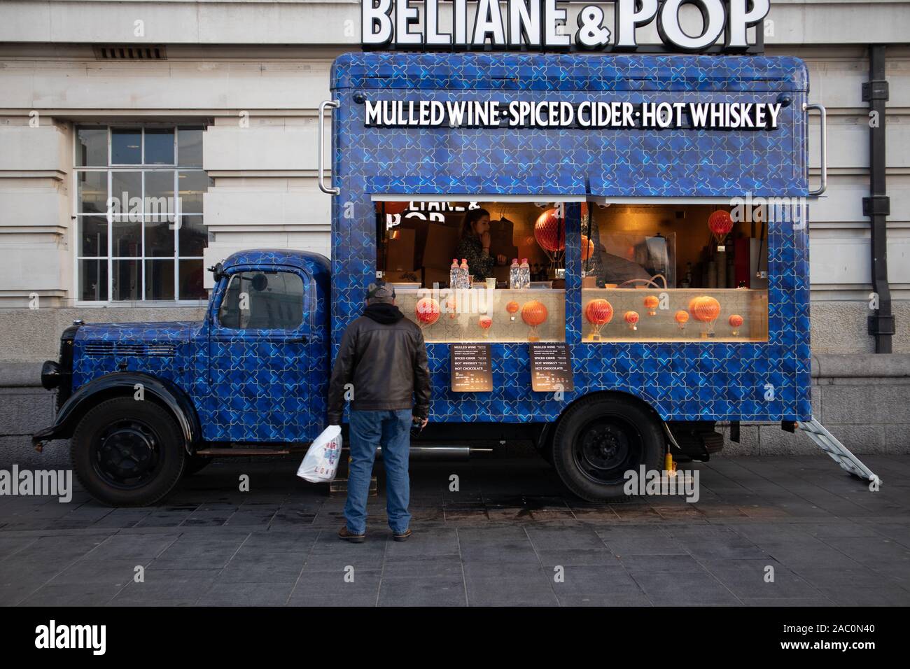 Man standing next to an alcoholic drinks street vendor in old blue van ...