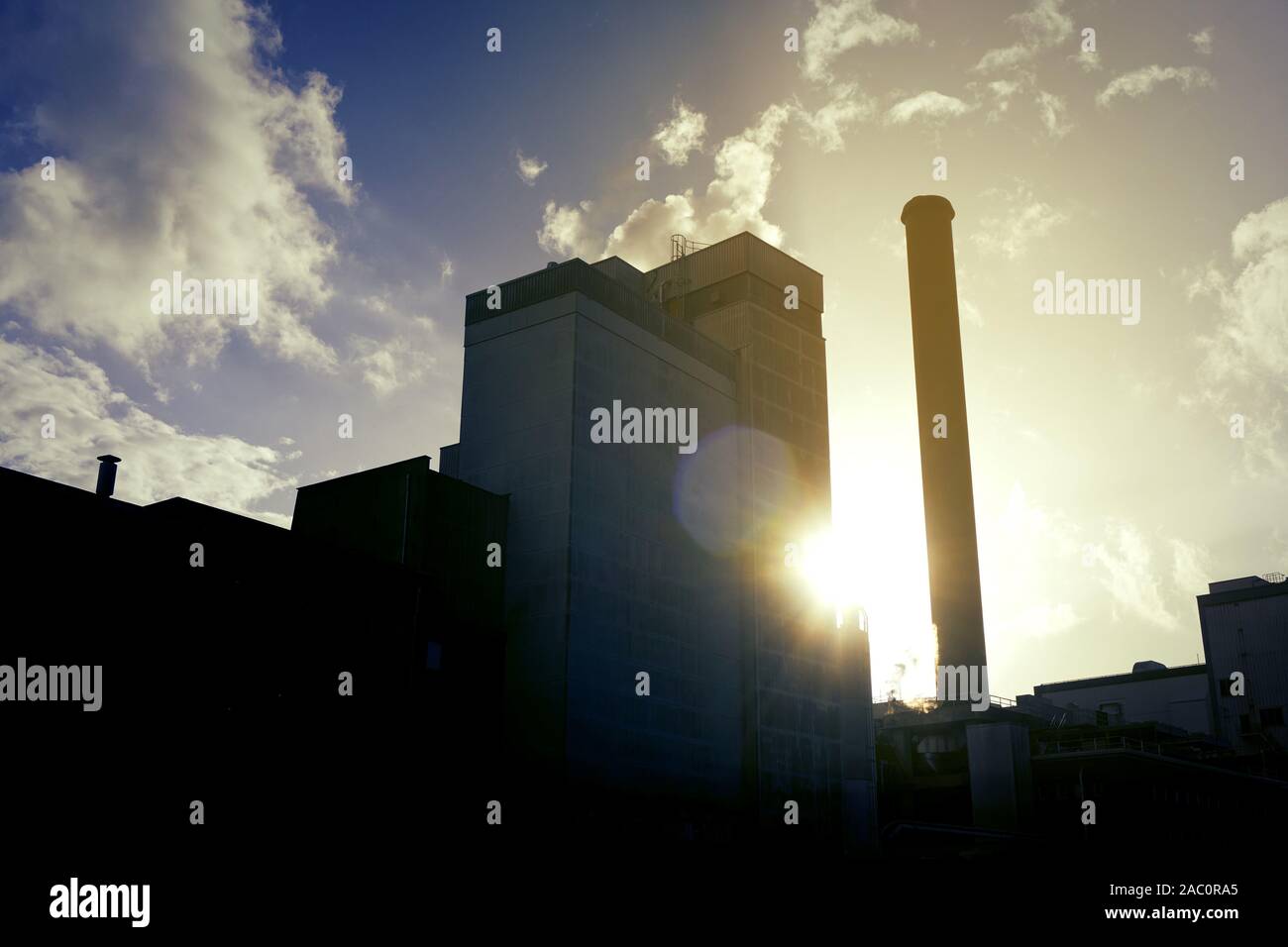 Silhouette of industry building and pipe backlit by the sun with lens ...
