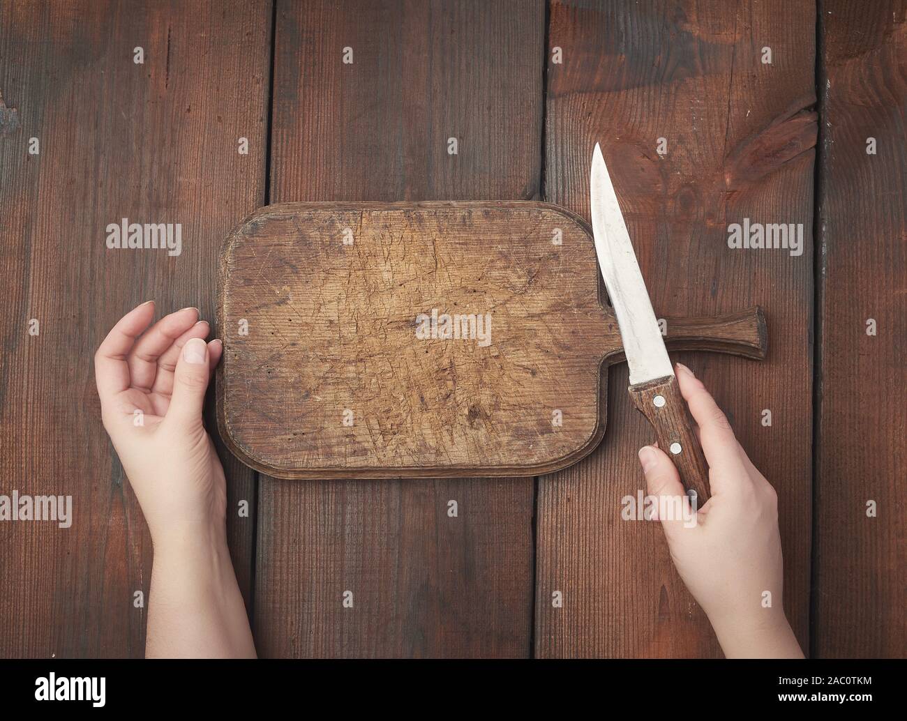 very old empty wooden rectangular cutting board and hands hold a sharp ...