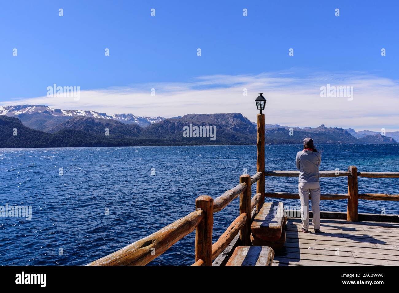 Rear view young woman on a wooden pier at Traful Lake against andes ...