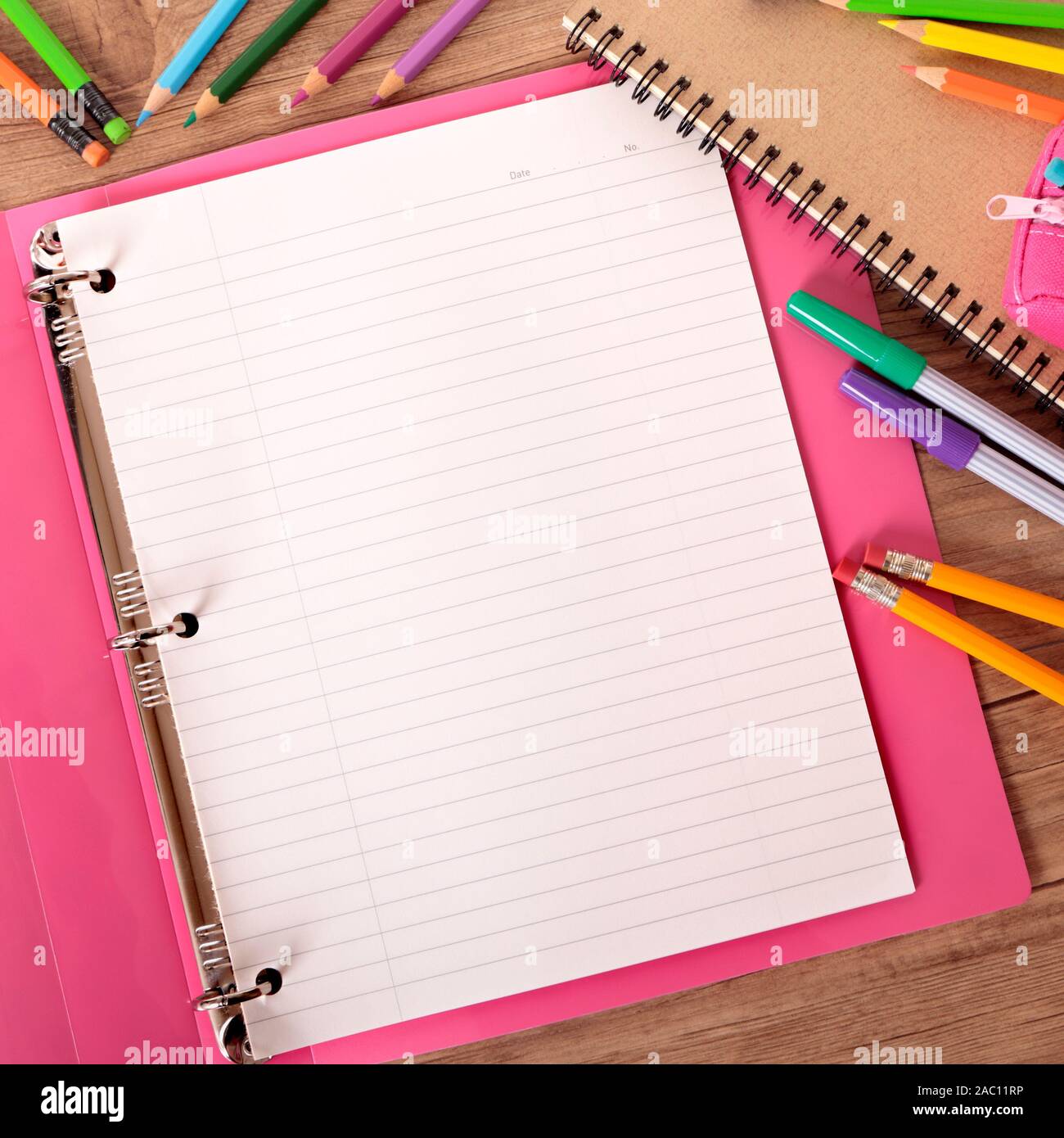 Busy student's desk with pink project folder surrounded by pens ...