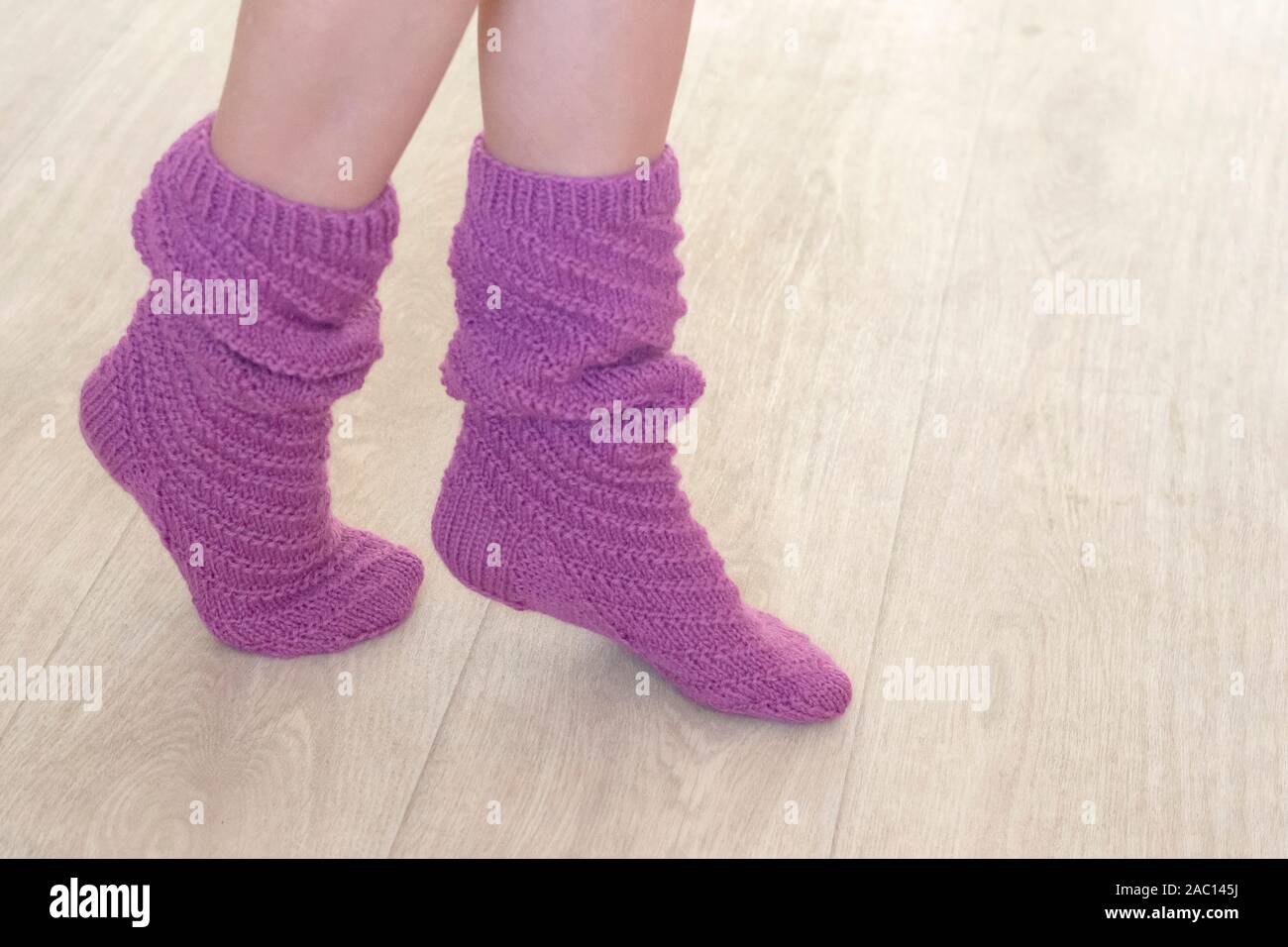 Female legs in high knitted socks of violet color on a beige background ...