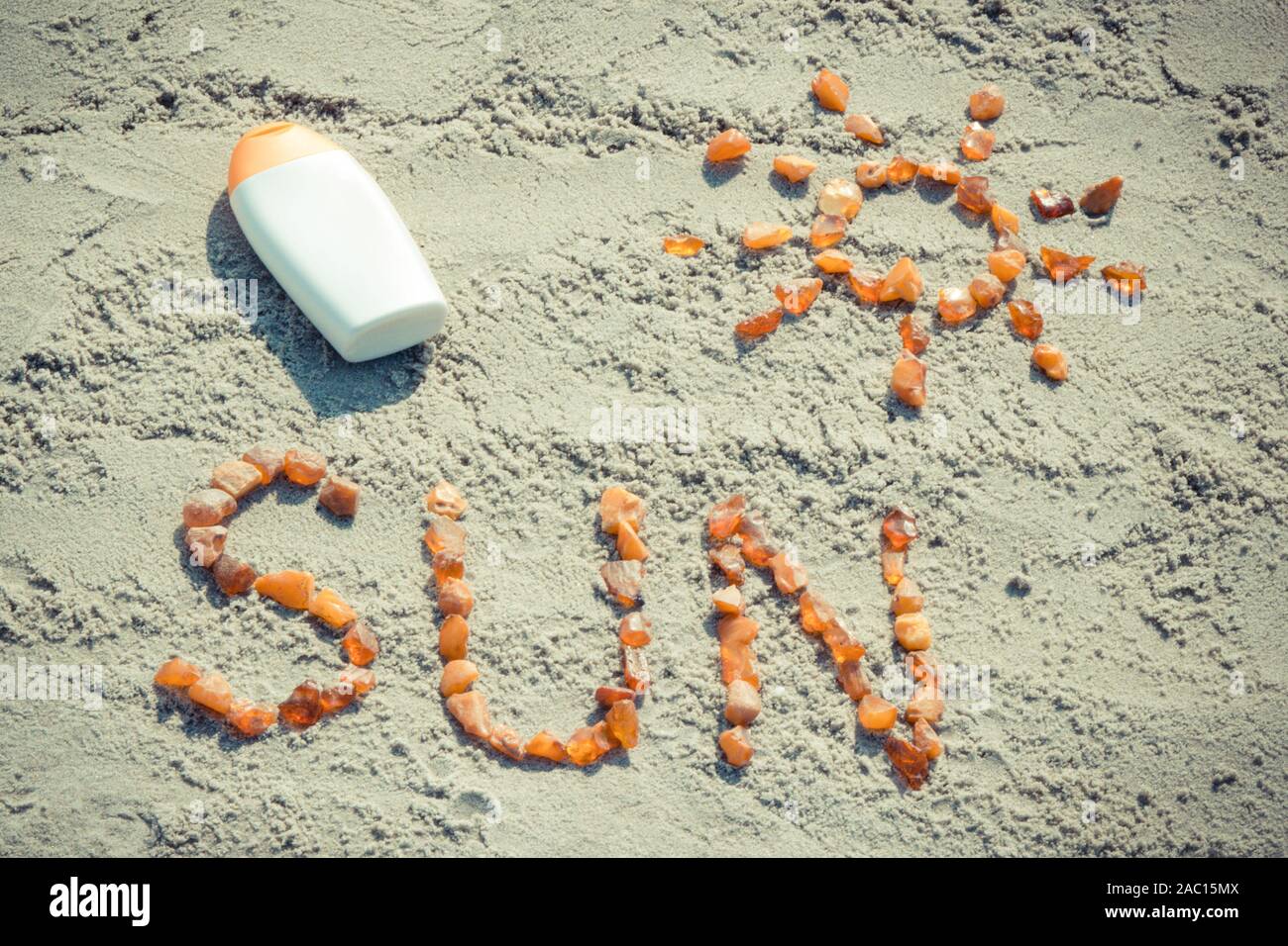 Inscription and shape of sun made of amber stones, sun lotion on sand ...