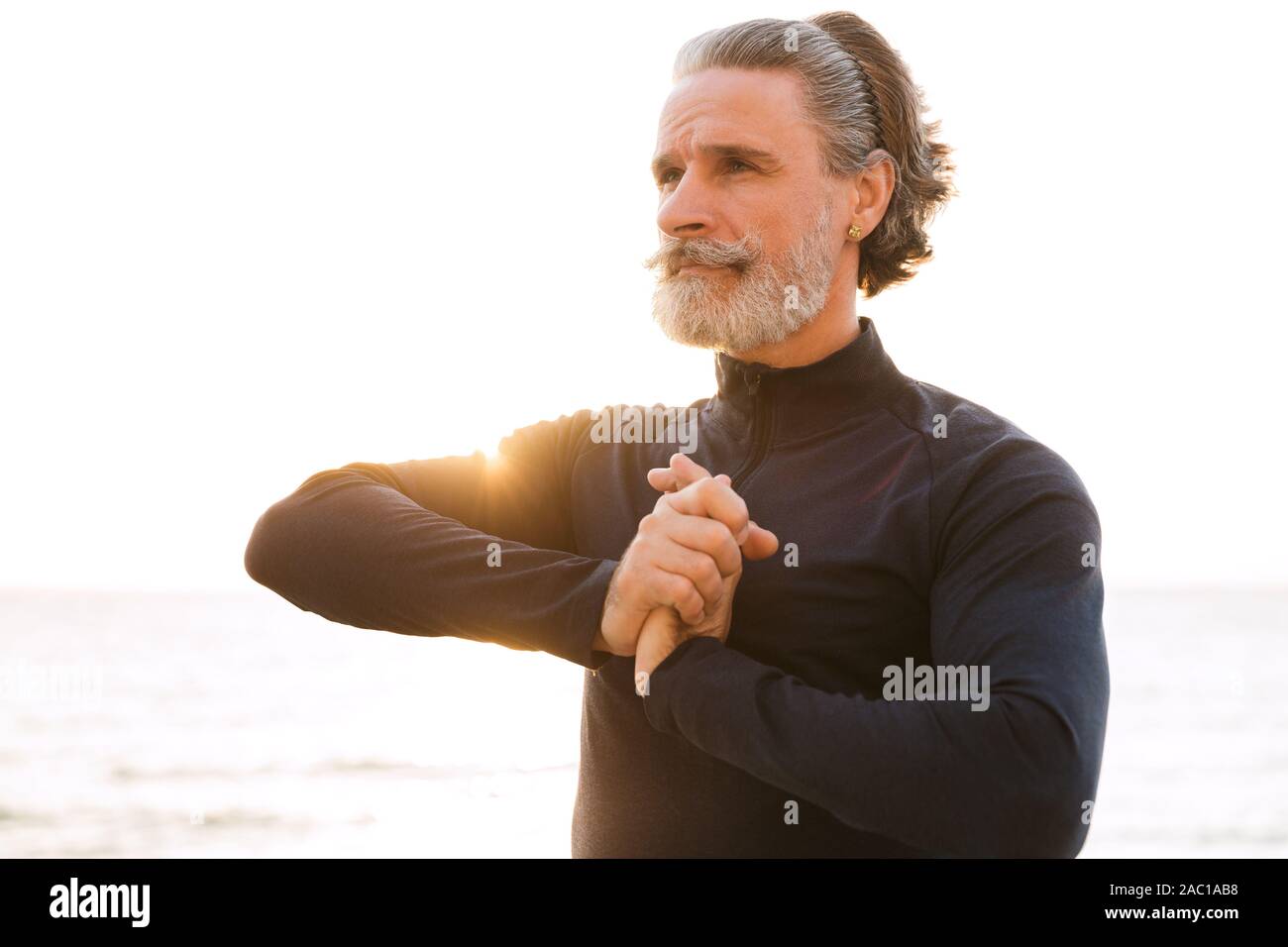 Image of sporty mature man in tracksuit doing exercise while working ...