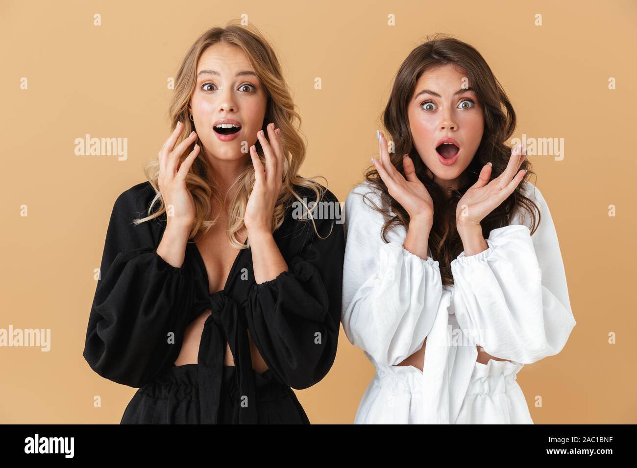 Portrait of two shocked women in black and white clothes looking at ...