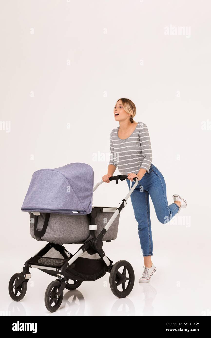 Full length of a beautiful young woman standing with a baby pram ...