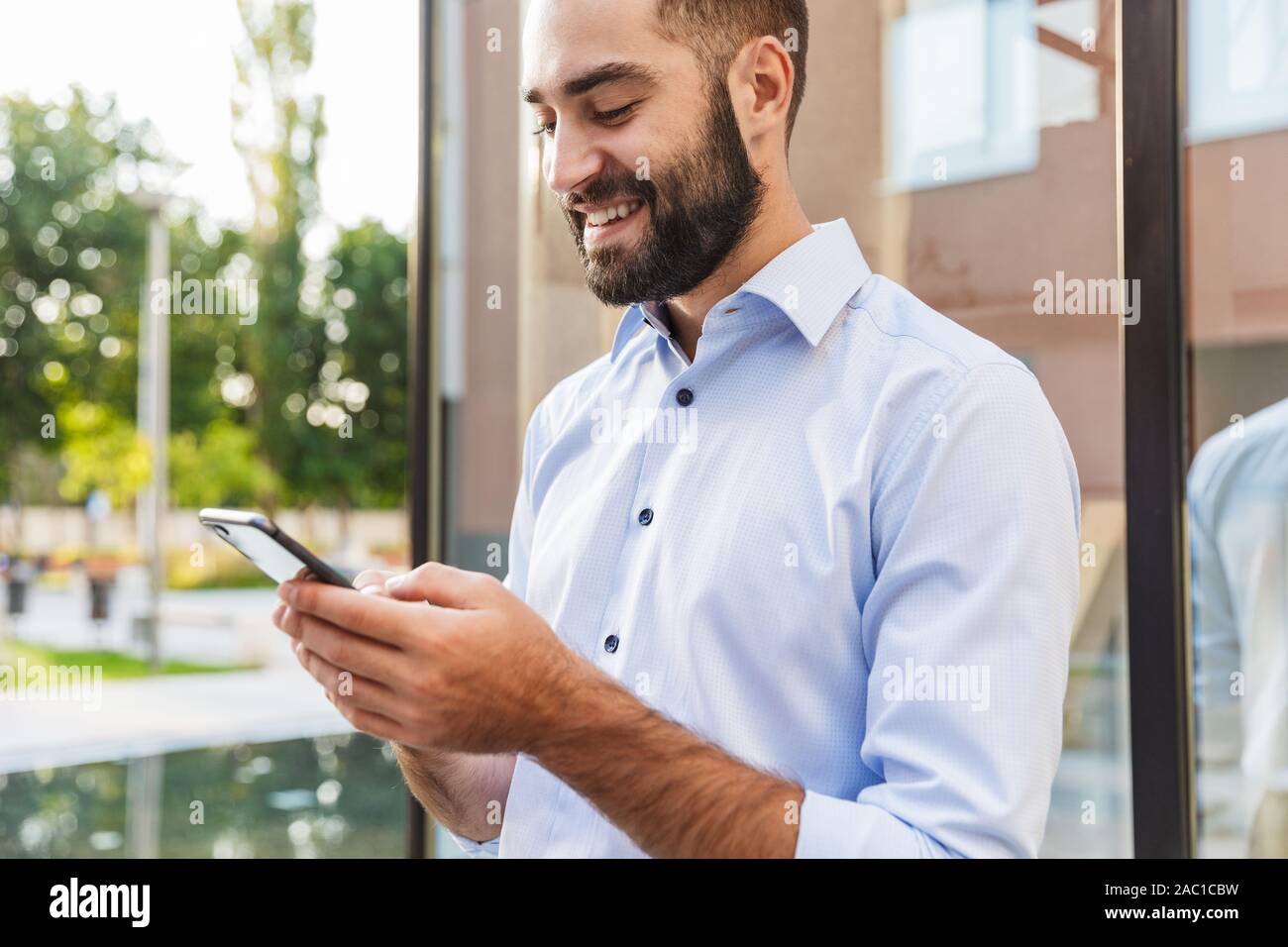 Photo of a young cheerful positive happy man outside at the street near ...