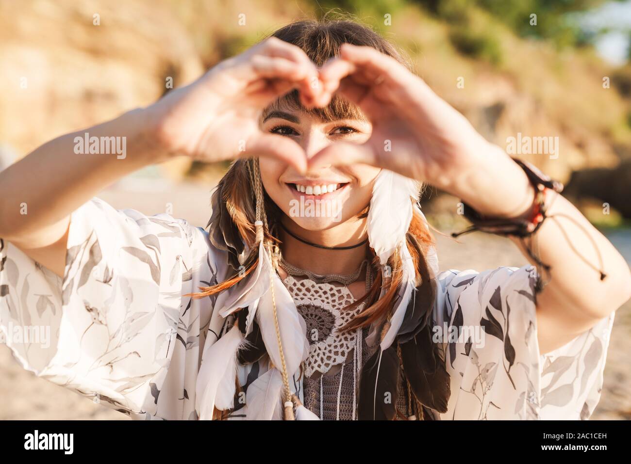 Image of lovely hippy girl in feather headband showing heart shape ...