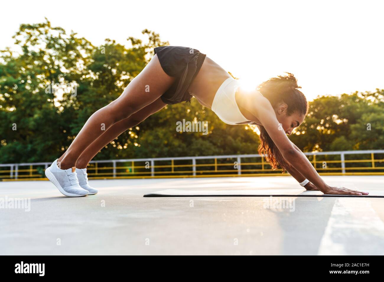 Photo of a concentrated young strong sports woman on rug outdoors make ...