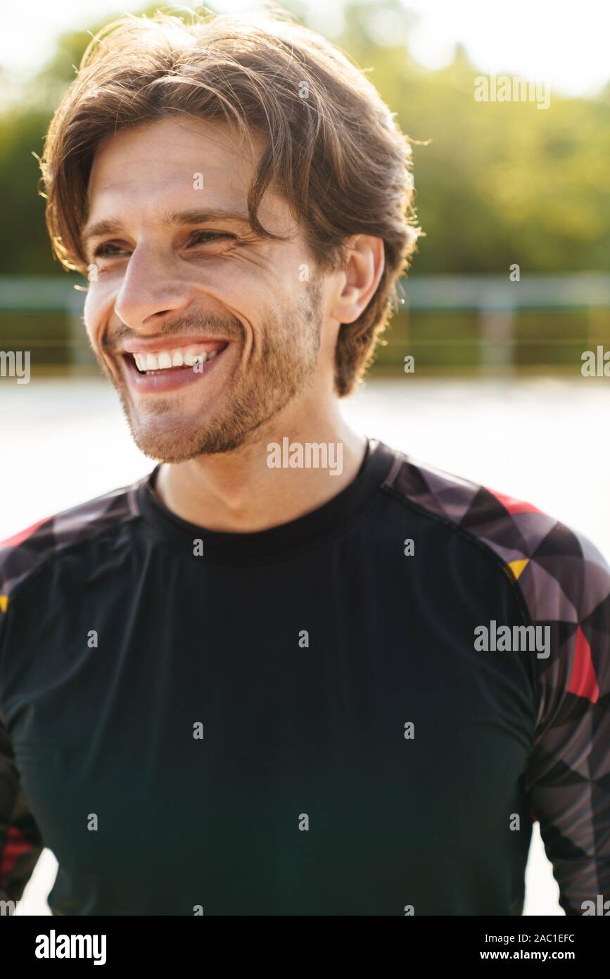 Photo of young masculine man wearing sports clothes smiling while ...