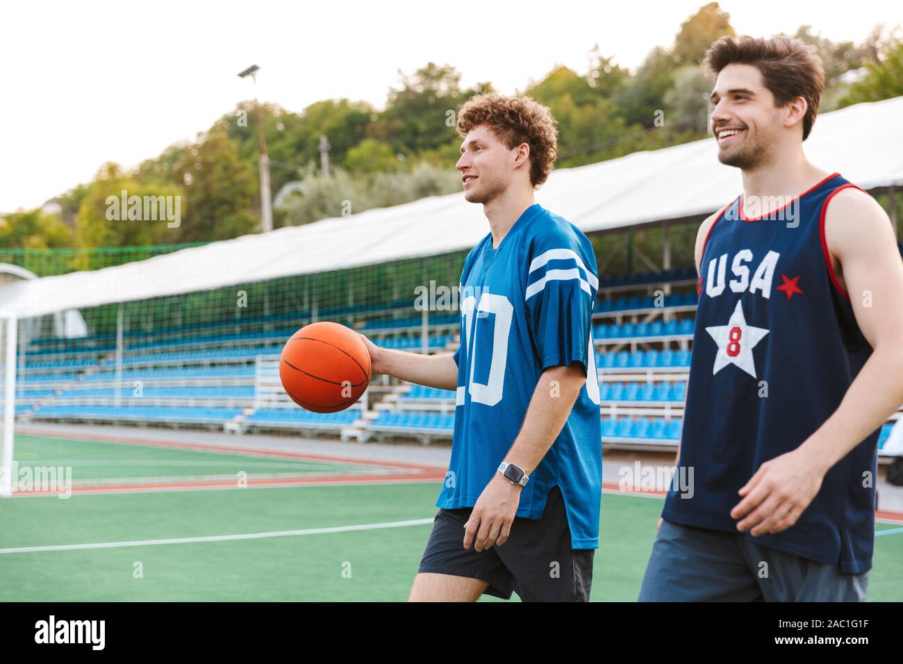 Two smiling confident basketball players walking at the playground ...