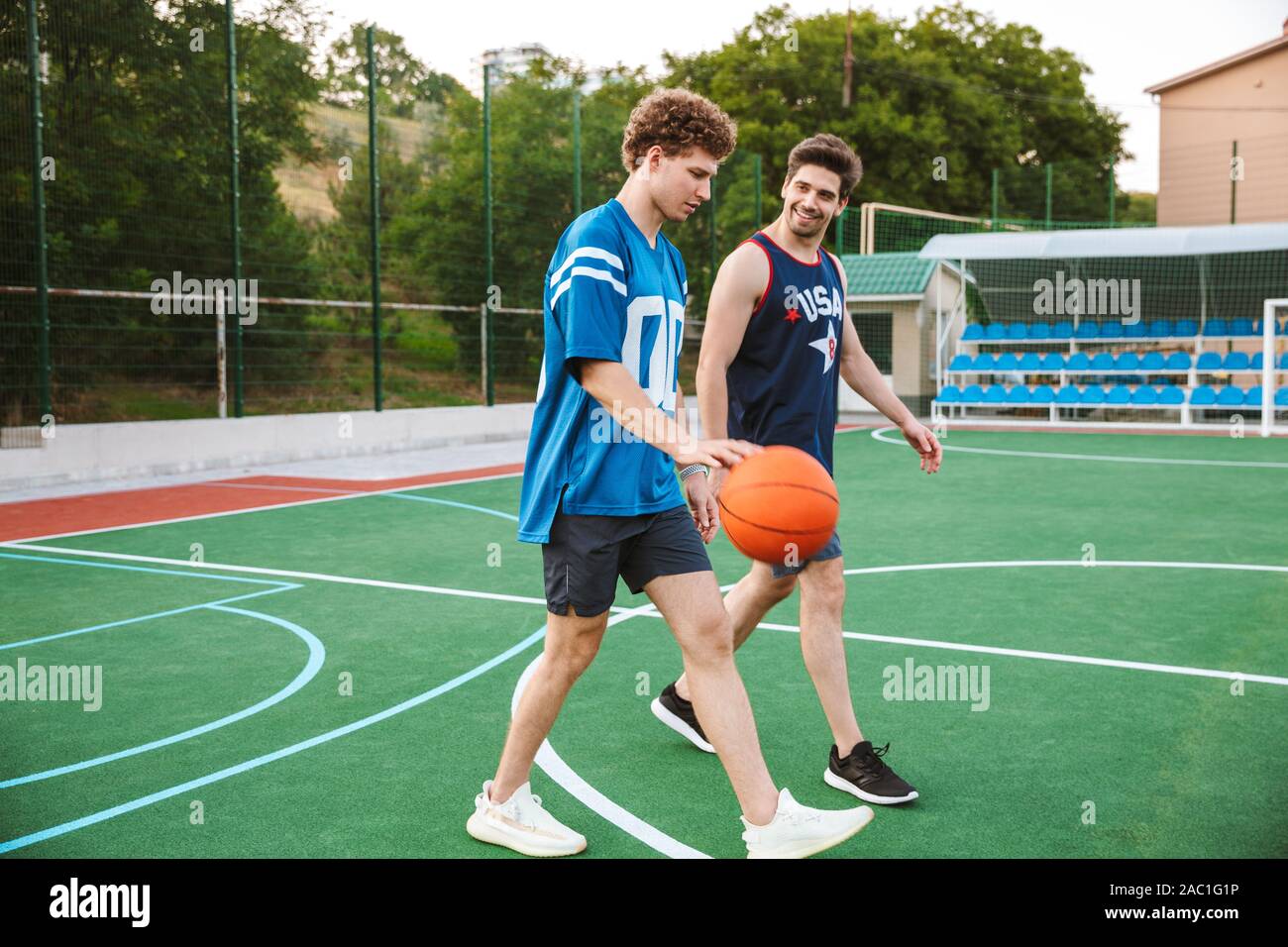 Two smiling confident basketball players walking at the playground ...