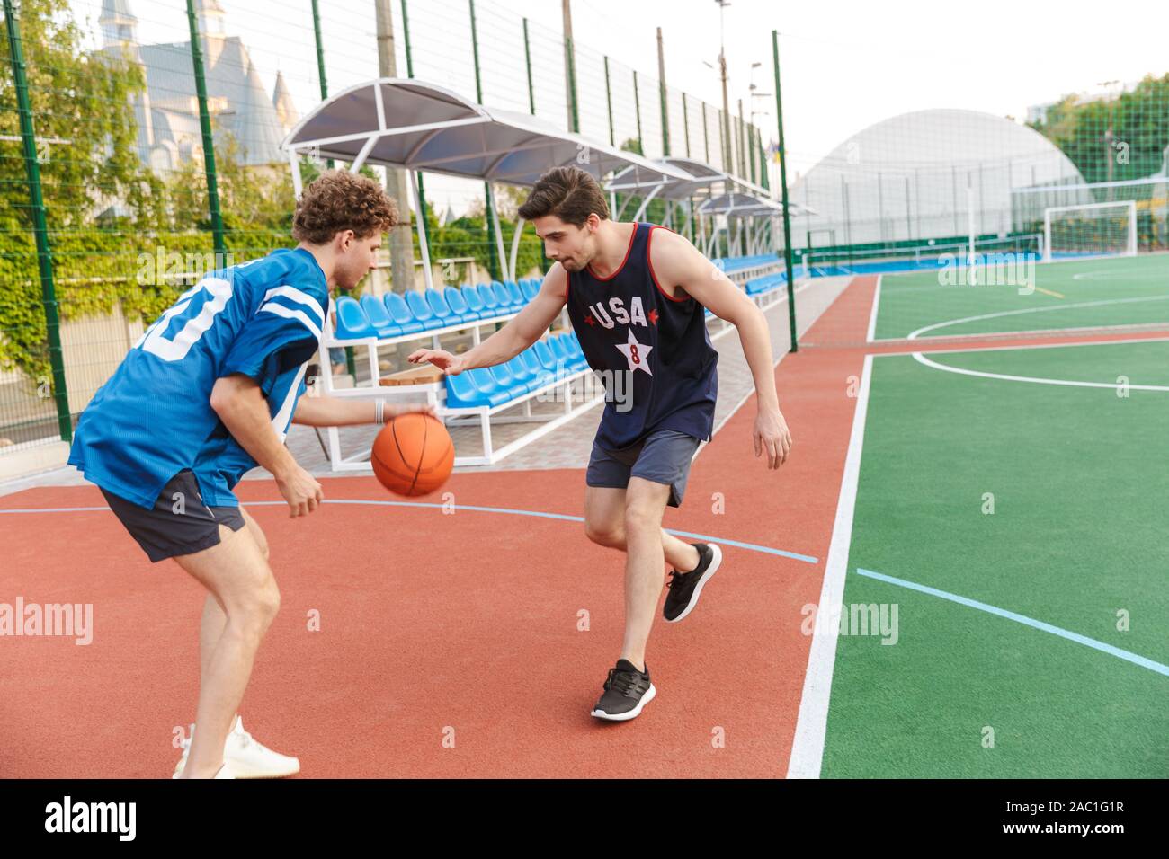 Two confident fit sportsmen playing basketball on a playground Stock ...