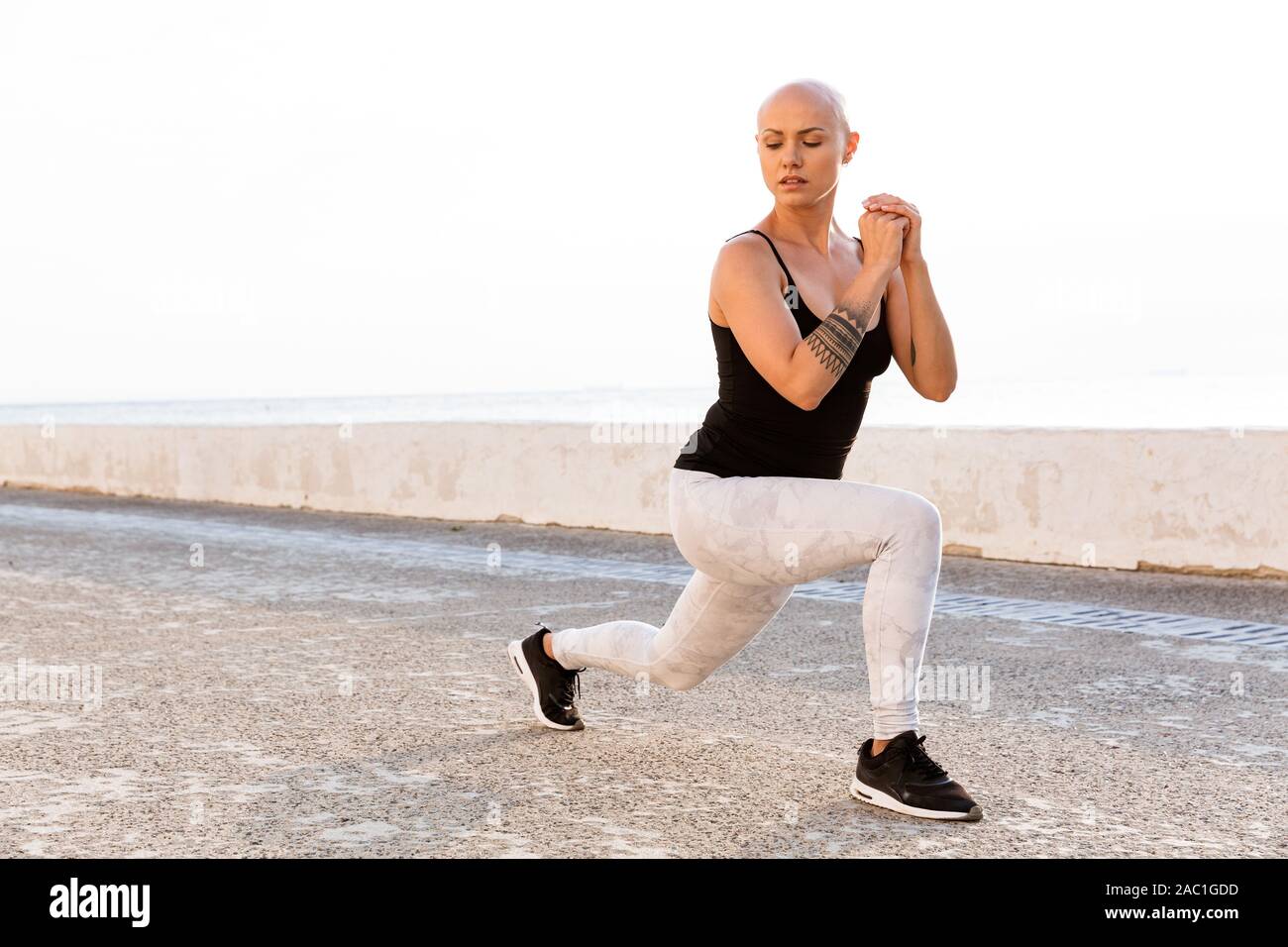 Image of concentrated bald woman in sportswear doing exercises while ...