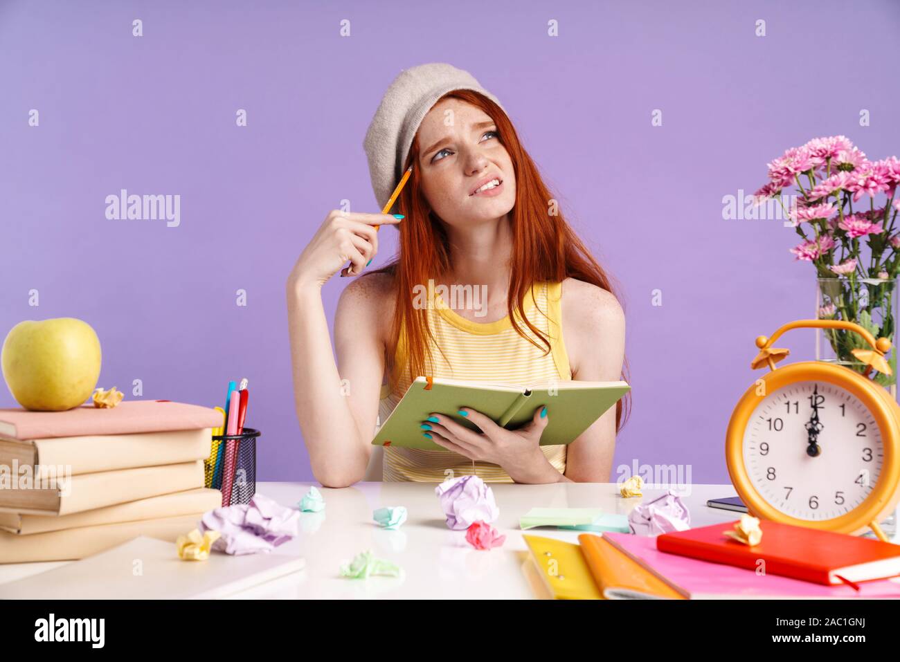 Photo of confused student girl writing in exercise book while doing ...