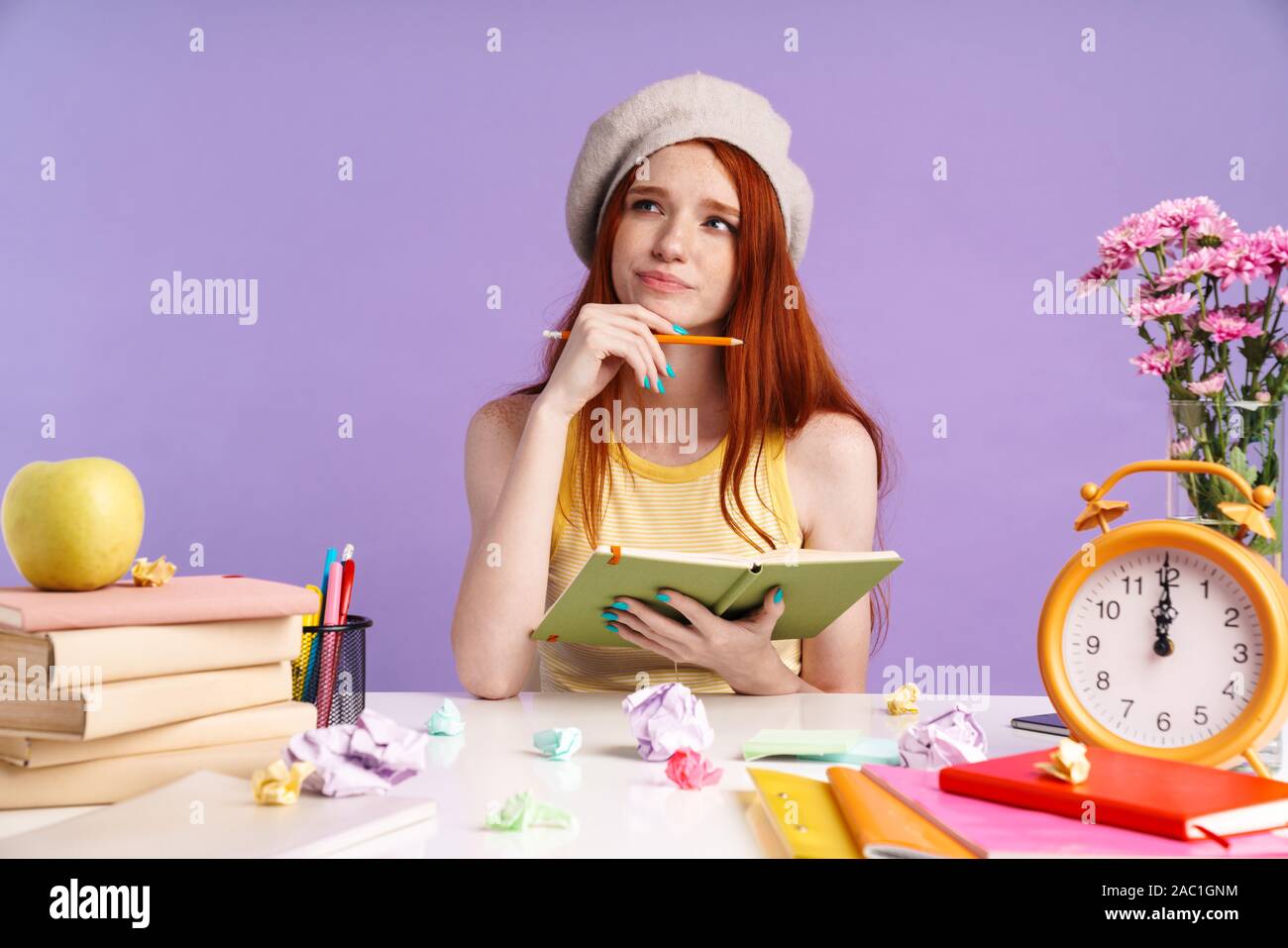 Photo of perplexed student girl writing in exercise book while doing ...