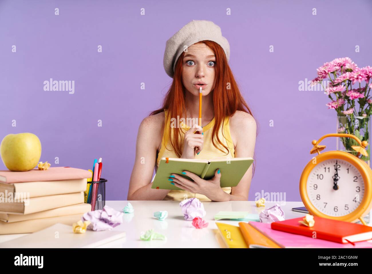 Photo of puzzled student girl writing in exercise book while doing ...