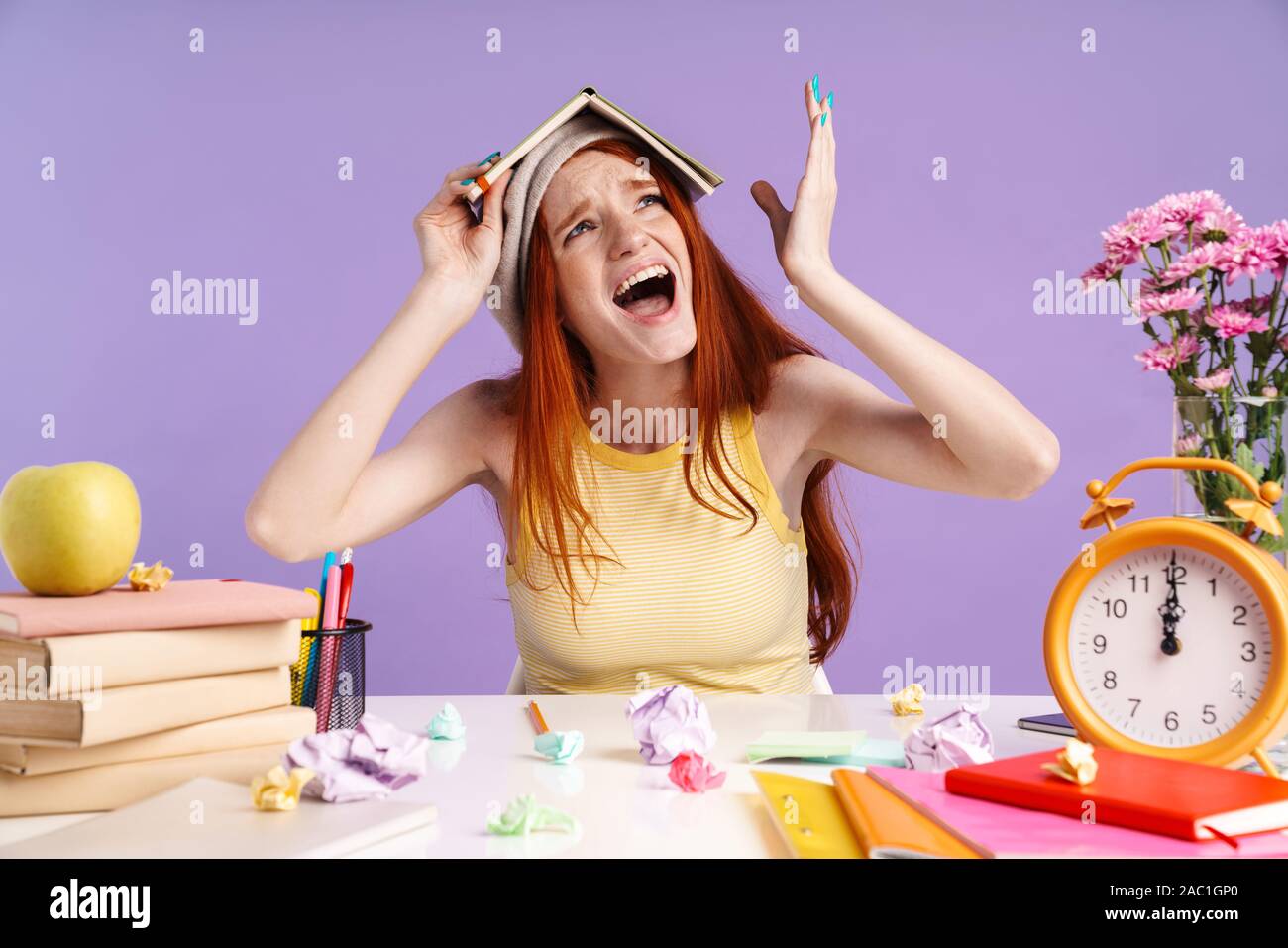 Photo of nervous student girl holding exercise book on her head while ...