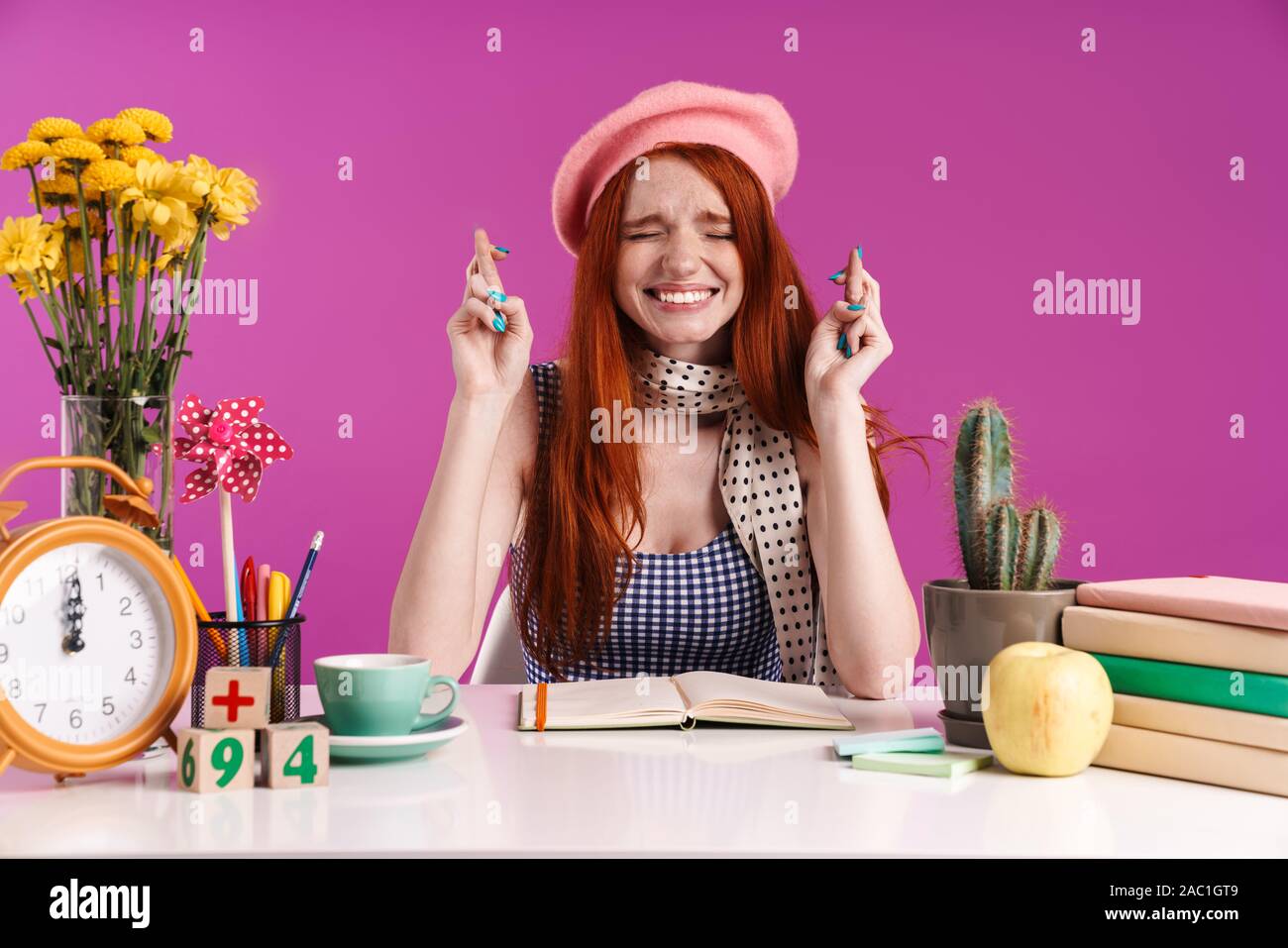 Image of tense teenage girl keeping fingers crossed while studying with ...