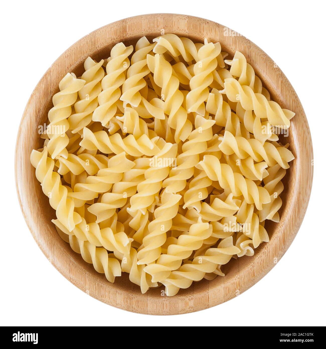 Uncooked rotini pasta in wooden bowl isolated on white background with ...