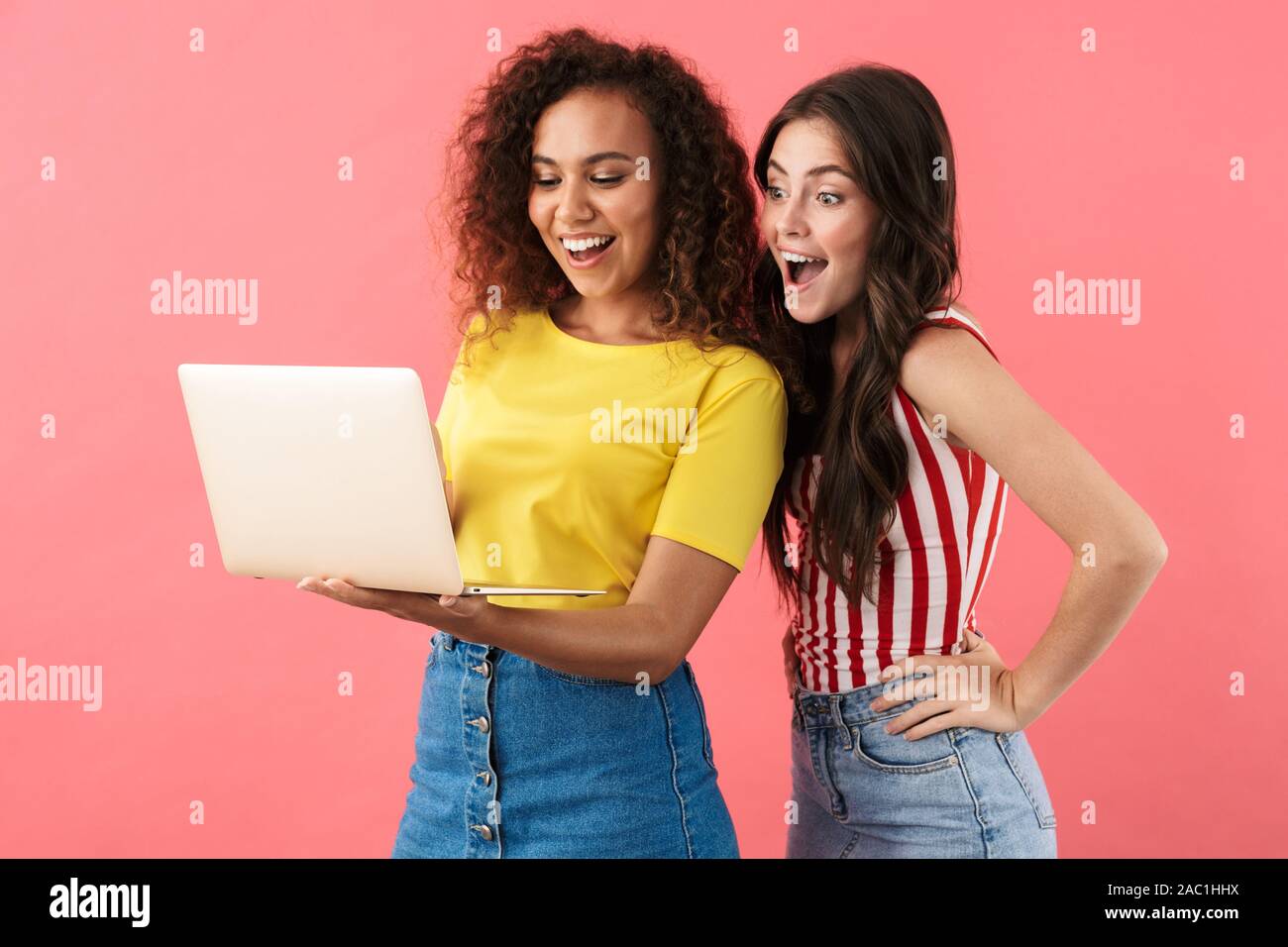 Image of delighted multinational girls rejoicing and holding laptop ...