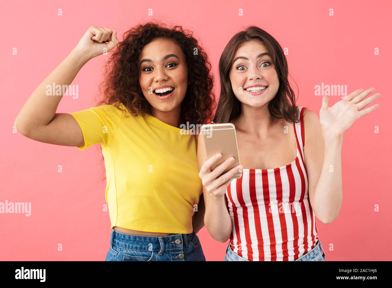 Image of joyous multinational girls rejoicing and looking at cellphone ...