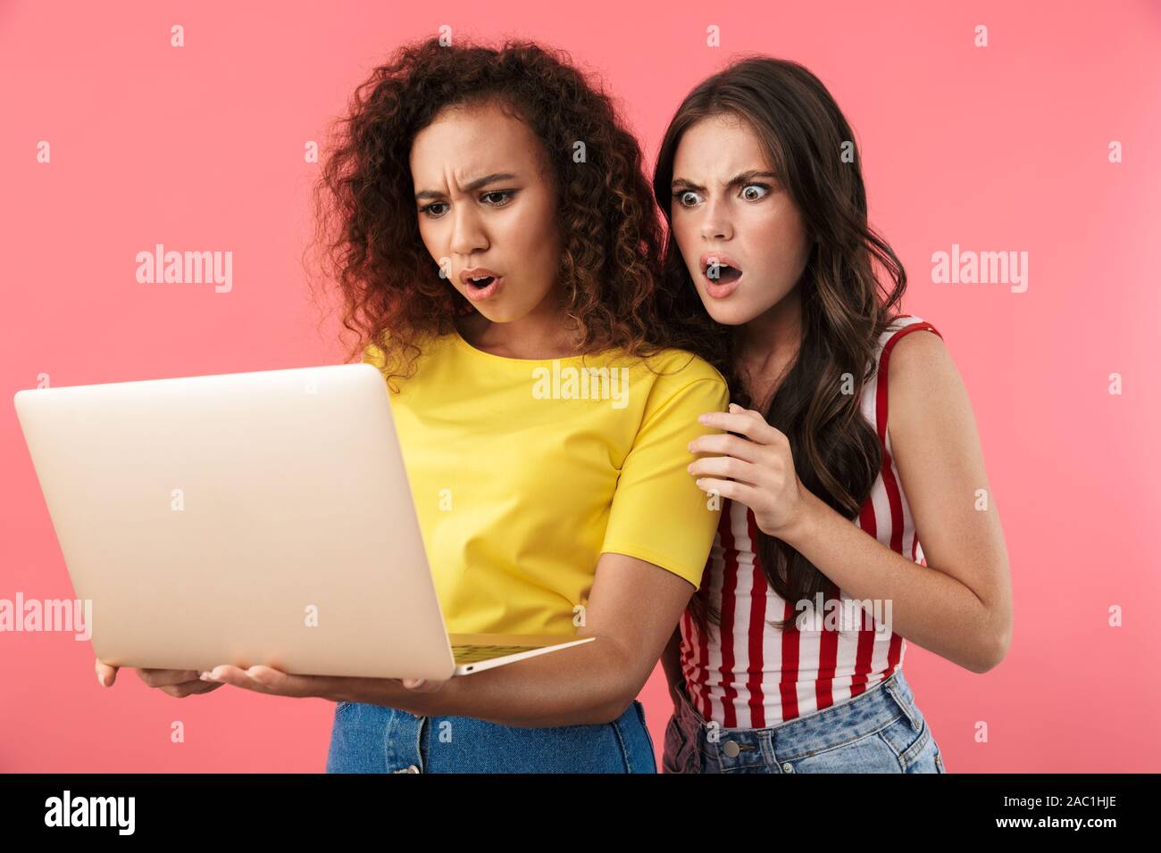 Image of shocked multinational girls wondering and holding laptop ...