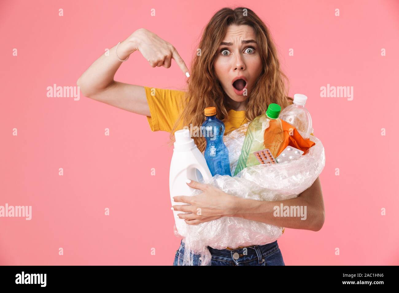 Photo of young irritated woman in basic t-shirt holding and pointing ...