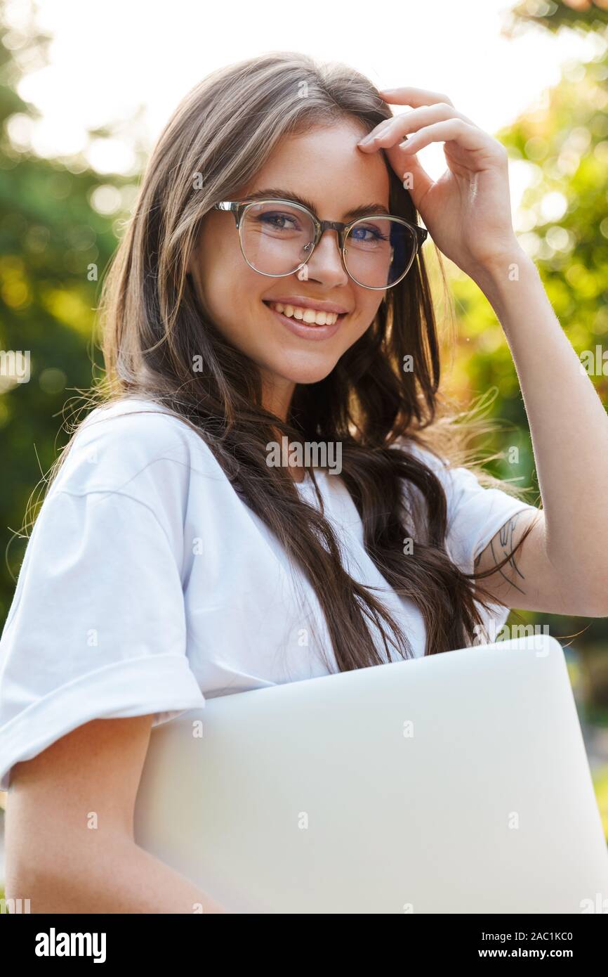 Photo of a smiling cheerful positive young student lady outdoors in ...