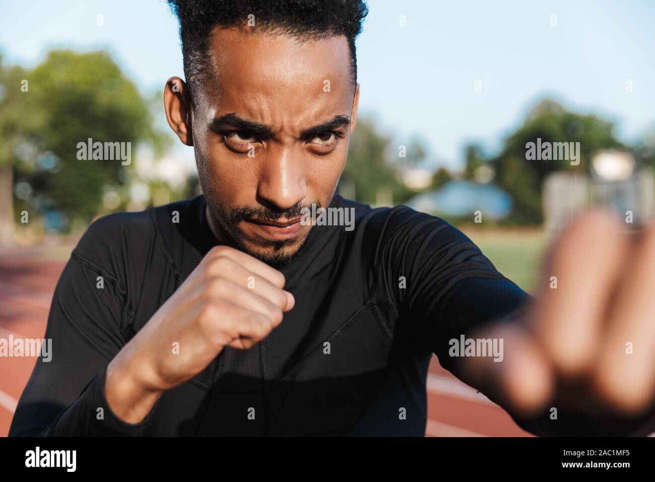 Image of focused african american man clenching fists and boxing on ...