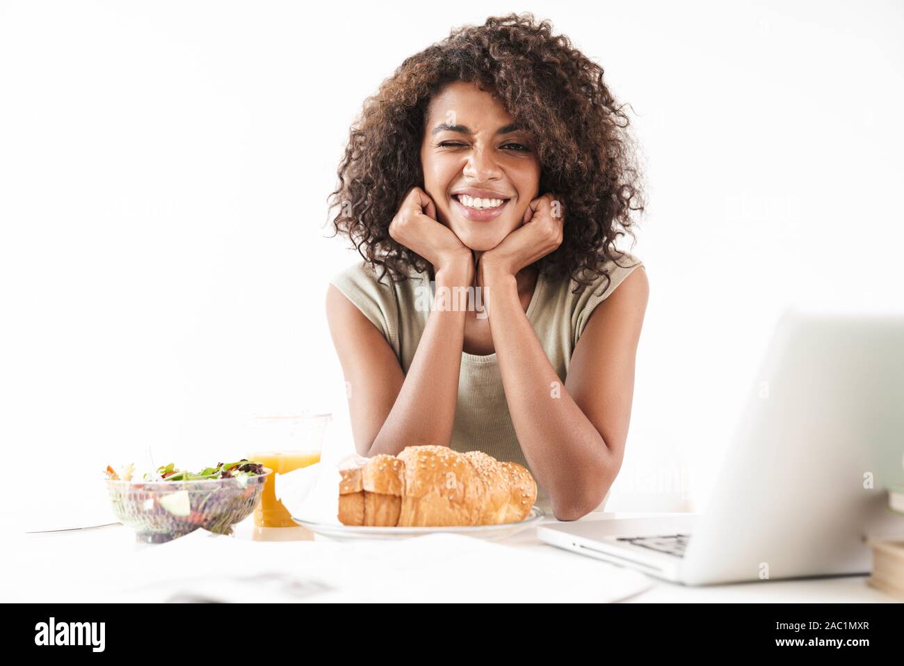 Beautiful smiling young african woman sitting at the desk isolated over ...