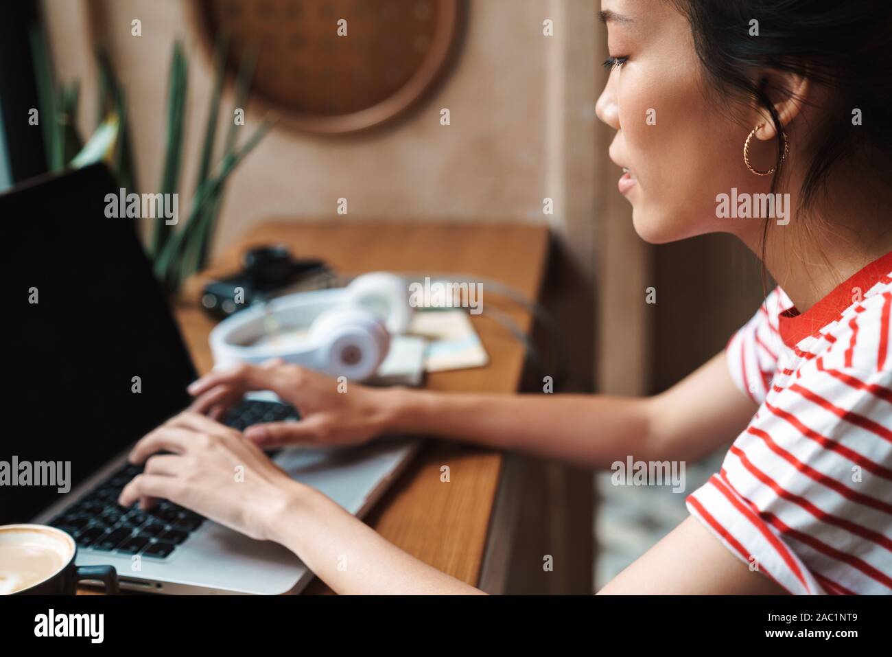 Cropped picture of a young beautiful asian woman sit in cafe using ...
