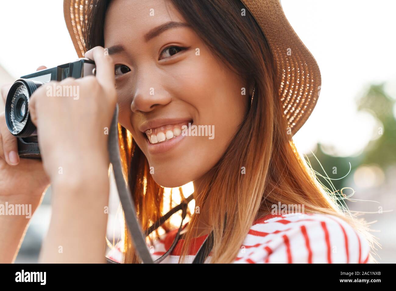 Portrait of adorable asian tourist woman photographing on retro camera ...
