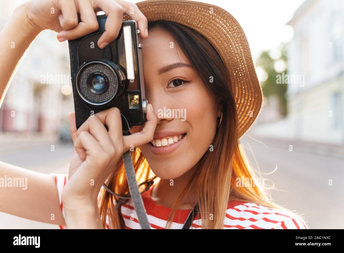 Portrait of joyful asian tourist woman photographing on retro camera ...