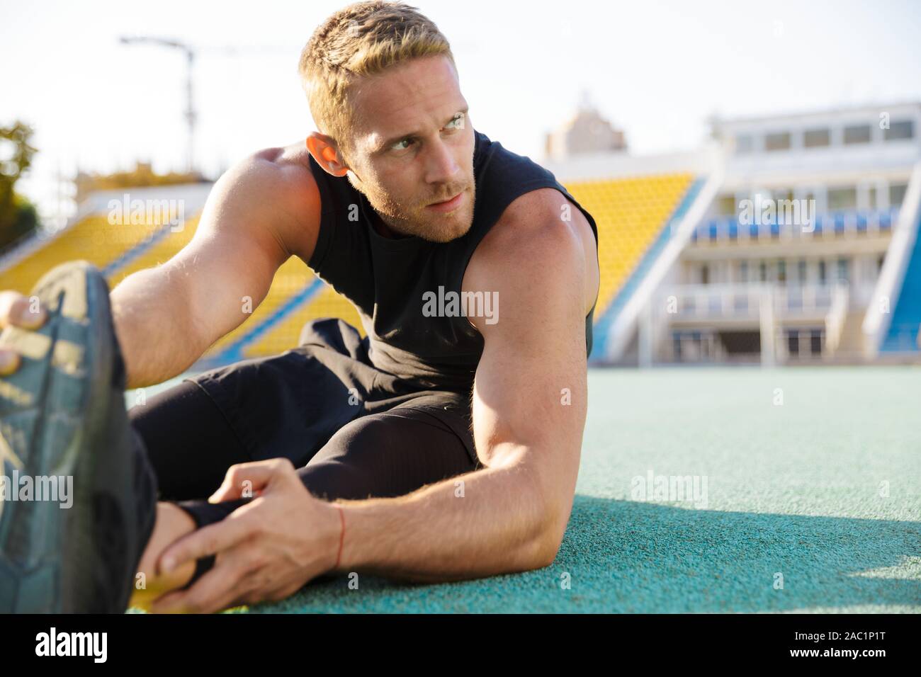 Image of strong man stretching his body at sports ground while doing ...